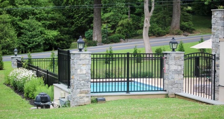 Black aluminum luxury pool fence with stone columns | Smucker Fencing